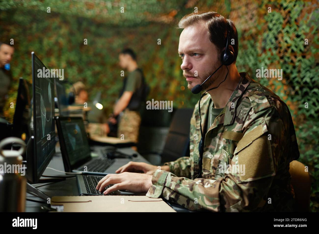 Young serious male operator with headset looking at graphic data on ...