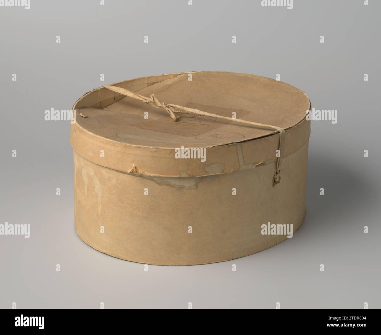 Oval hat box of cardboard with loose lid, covered with beige rip paper ...