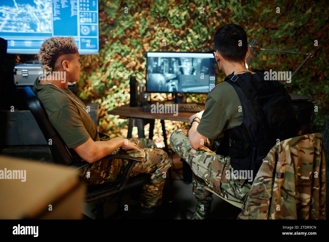 Two young intercultural male and female officers looking at computer ...