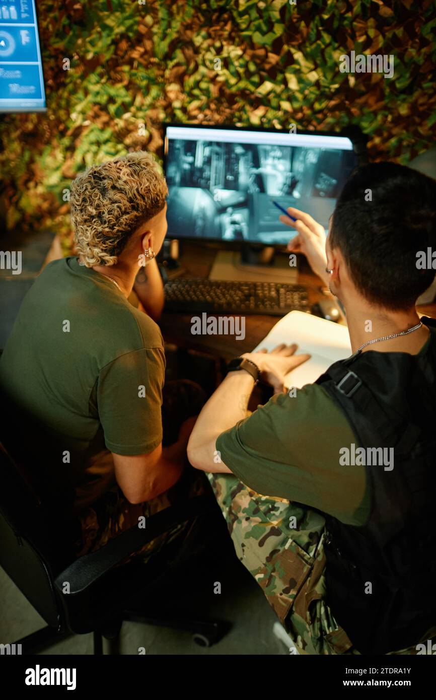 Young confident male officer pointing at computer screen while ...