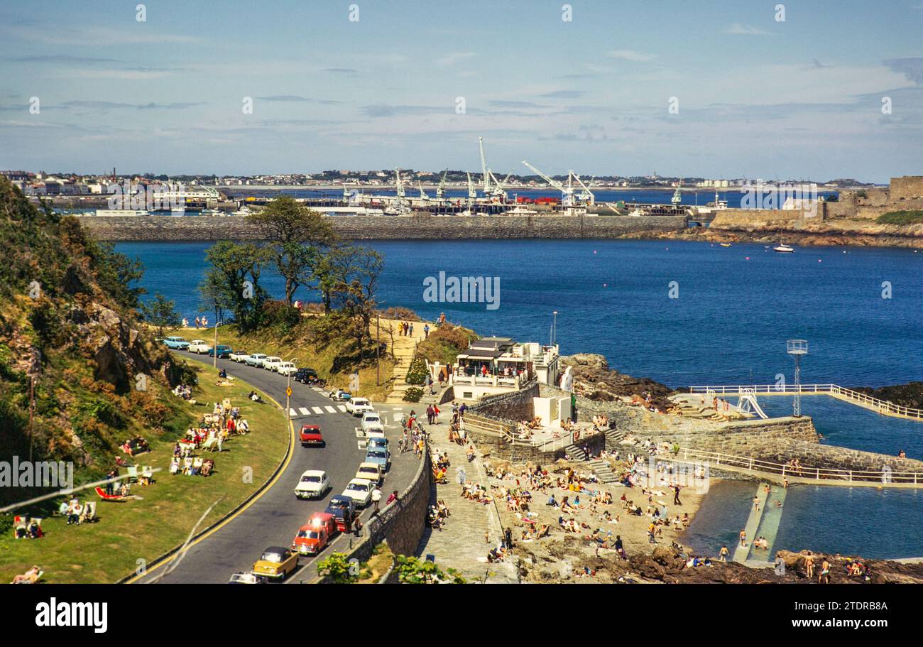 People sunbathing by coast, St Peter Port, Guernsey, Channel Islands ...