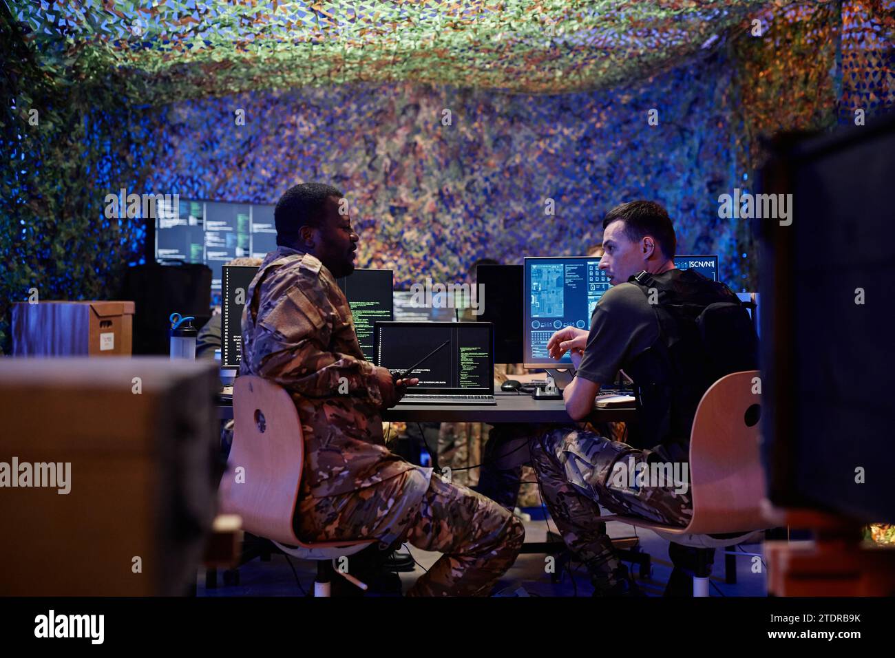 Young male officer in body armor explaining something to African ...