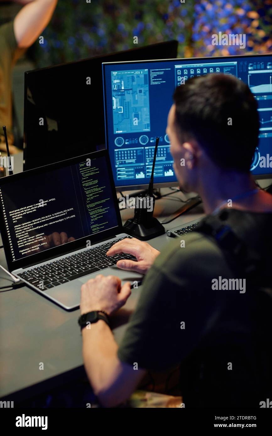 Young male military officer in uniform looking through data on laptop ...