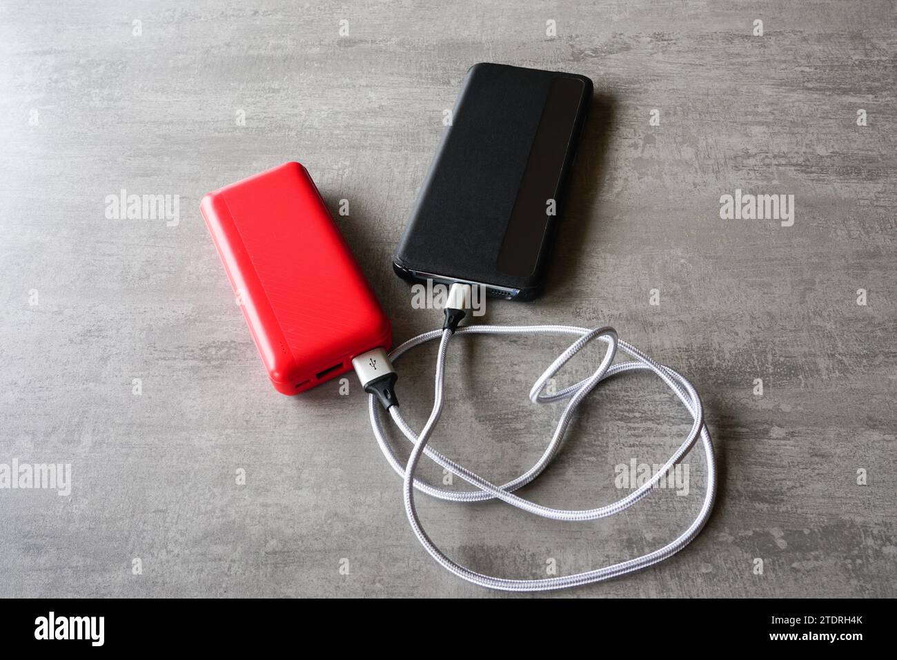 Modern black smart phone charging with help of red power bank ...