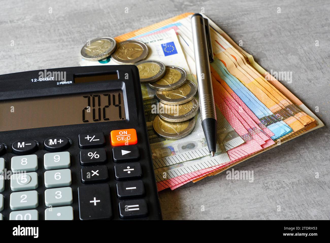 Calculator with number 2024 on display, pen, euro banknotes and coins ...