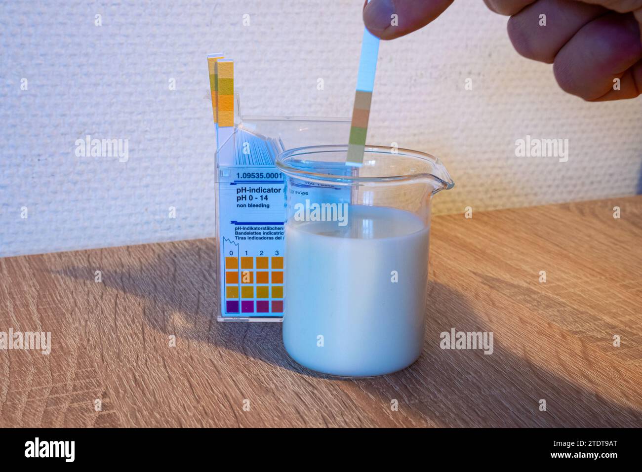 Person determines the acidity of a liquid using a pH strip. Used in ...