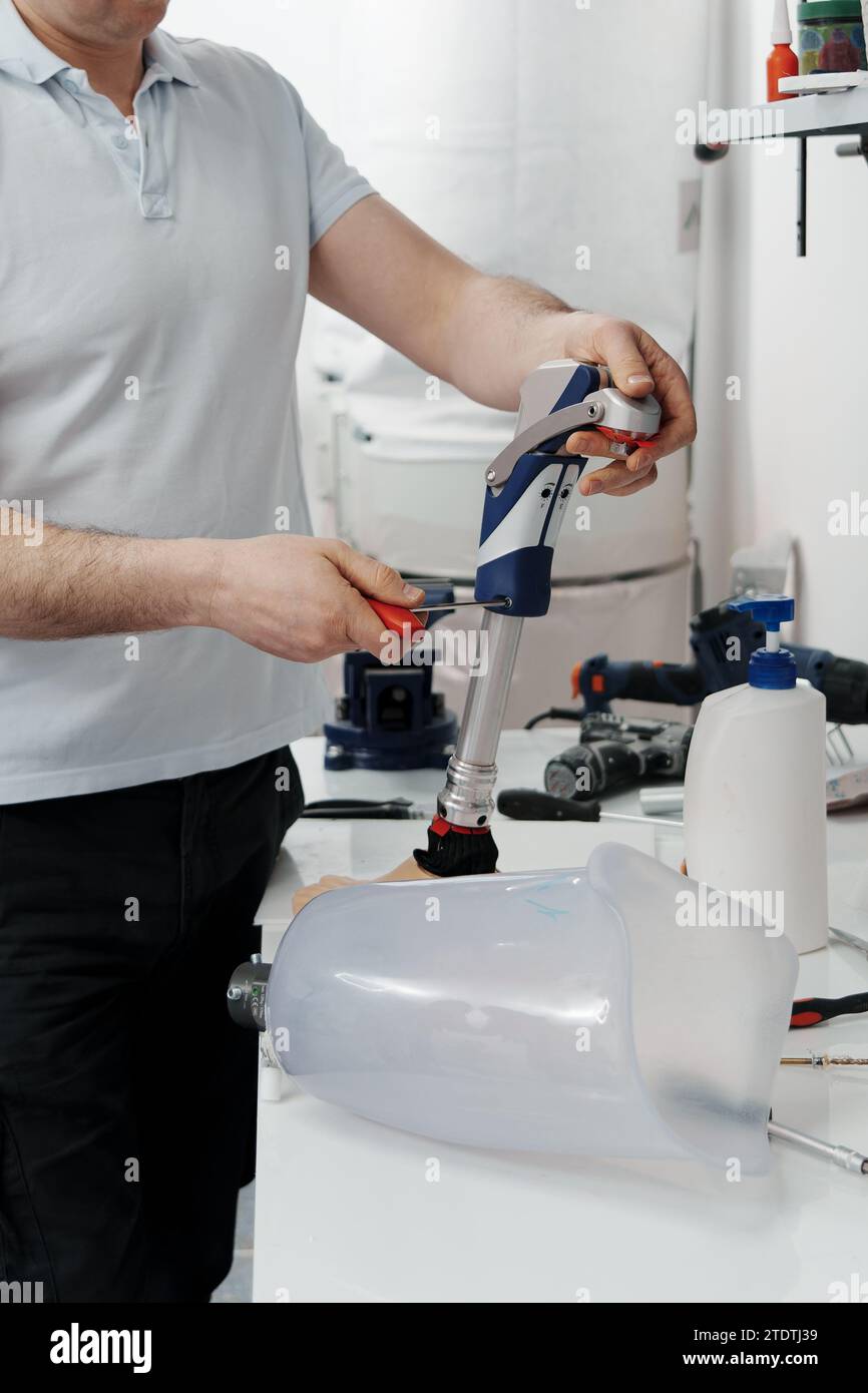 Crop unrecognizable craftsman adjusting and bending modern prosthetic ...