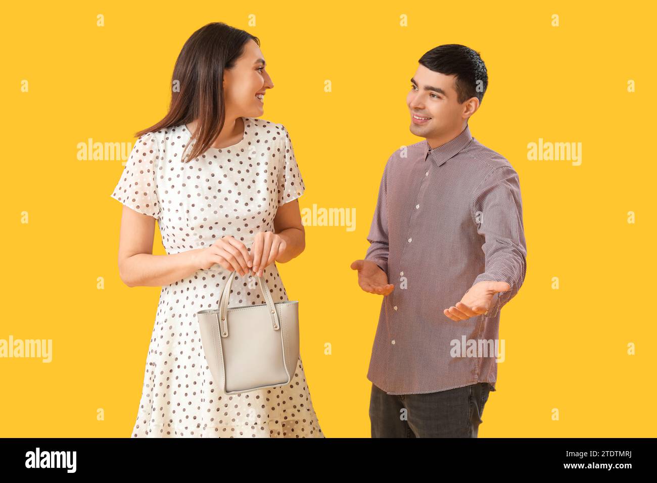 Young man letting his girlfriend go first on yellow background Stock ...