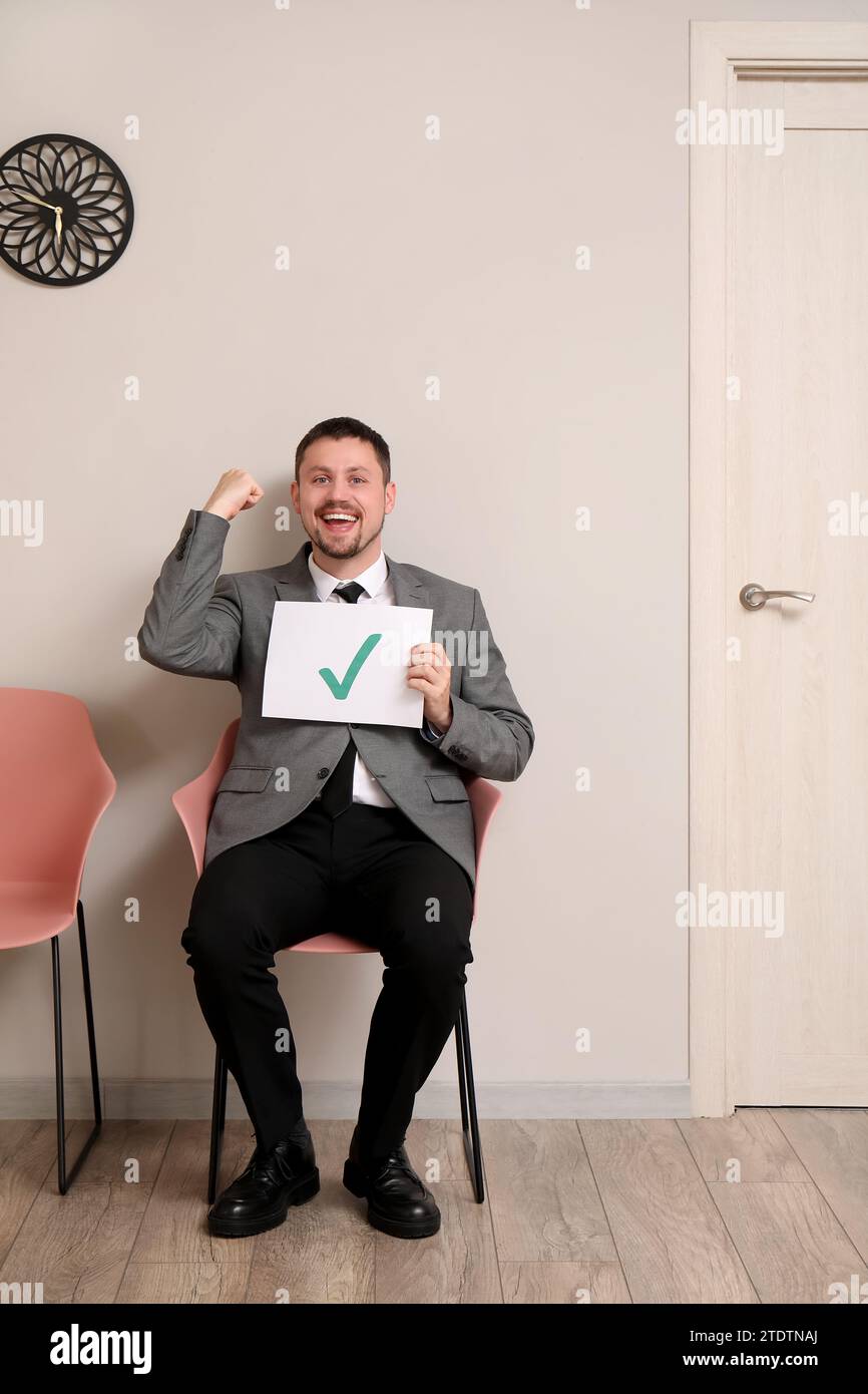 Happy male applicant holding paper sheet with check mark in room Stock ...