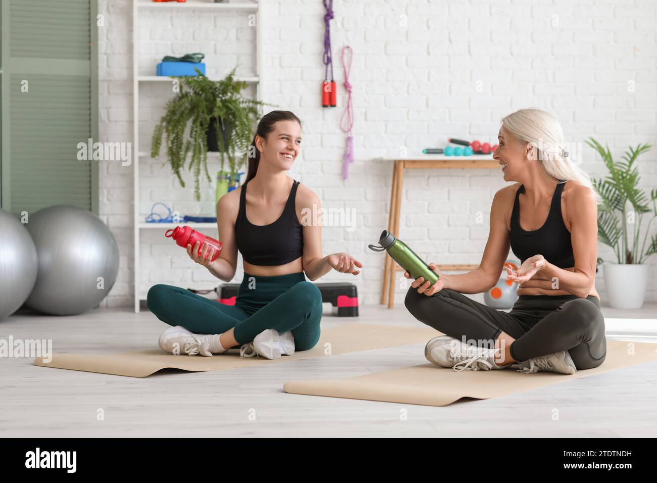 Body positive women with bottles of water in gym Stock Photo - Alamy