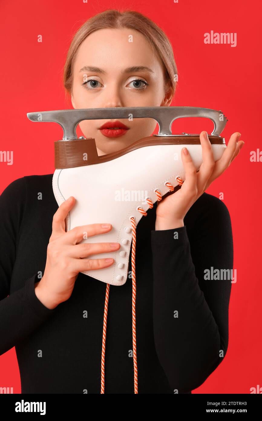 Beautiful female figure skater with ice skate on red background Stock ...