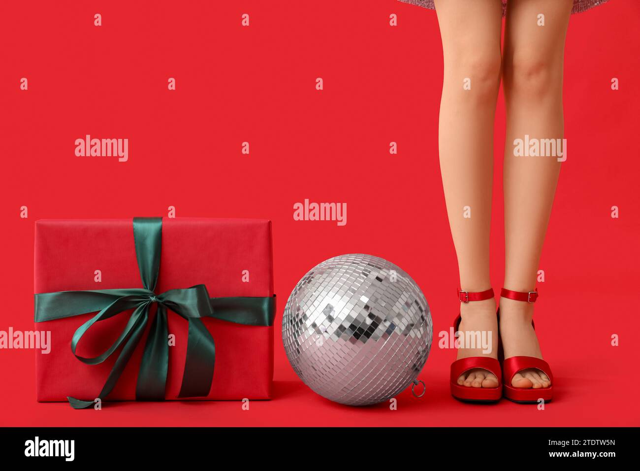 Female legs in trendy high heels with disco ball and gift box on red ...