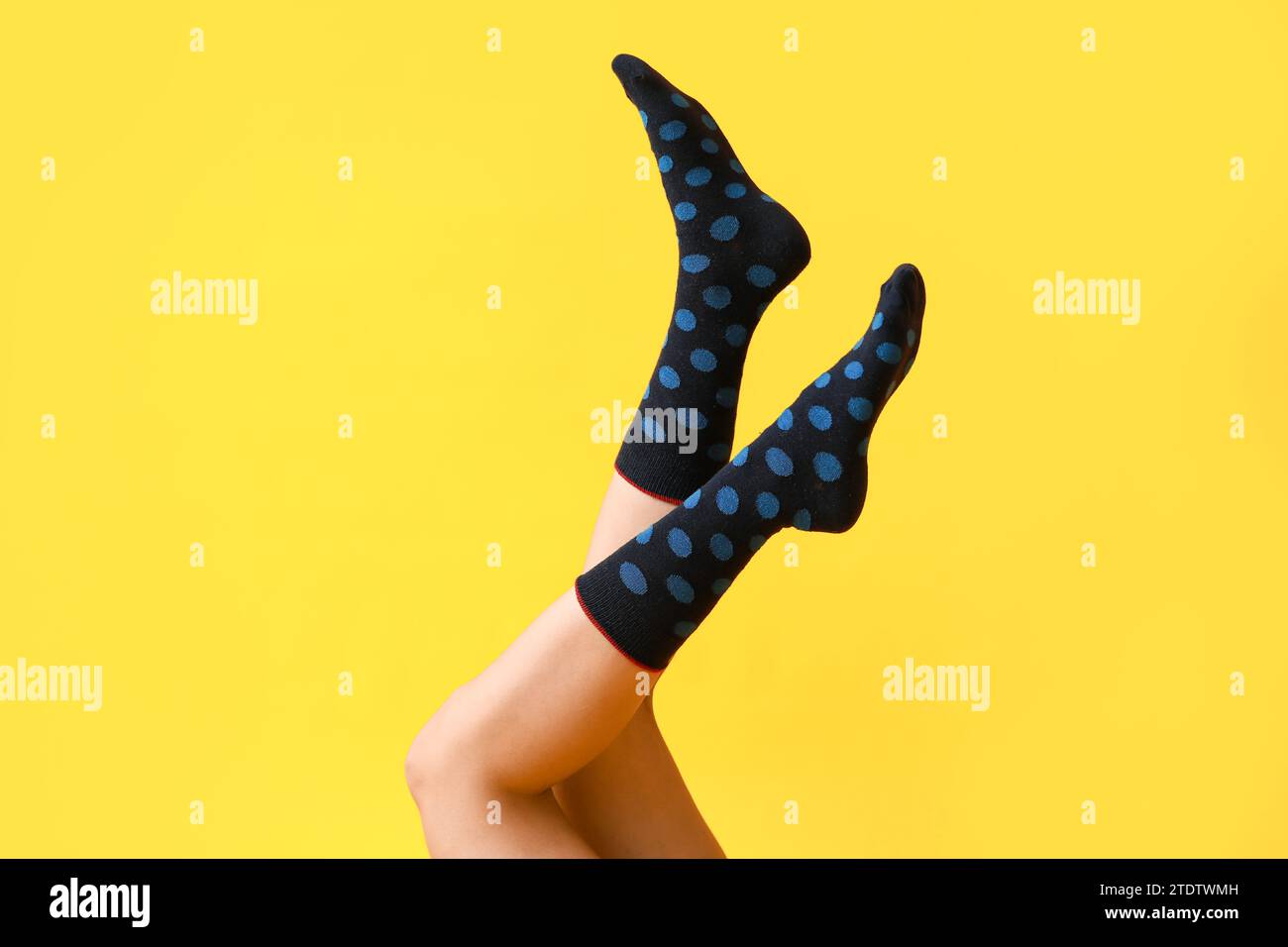 Legs of young woman in black dotted socks on yellow background Stock ...