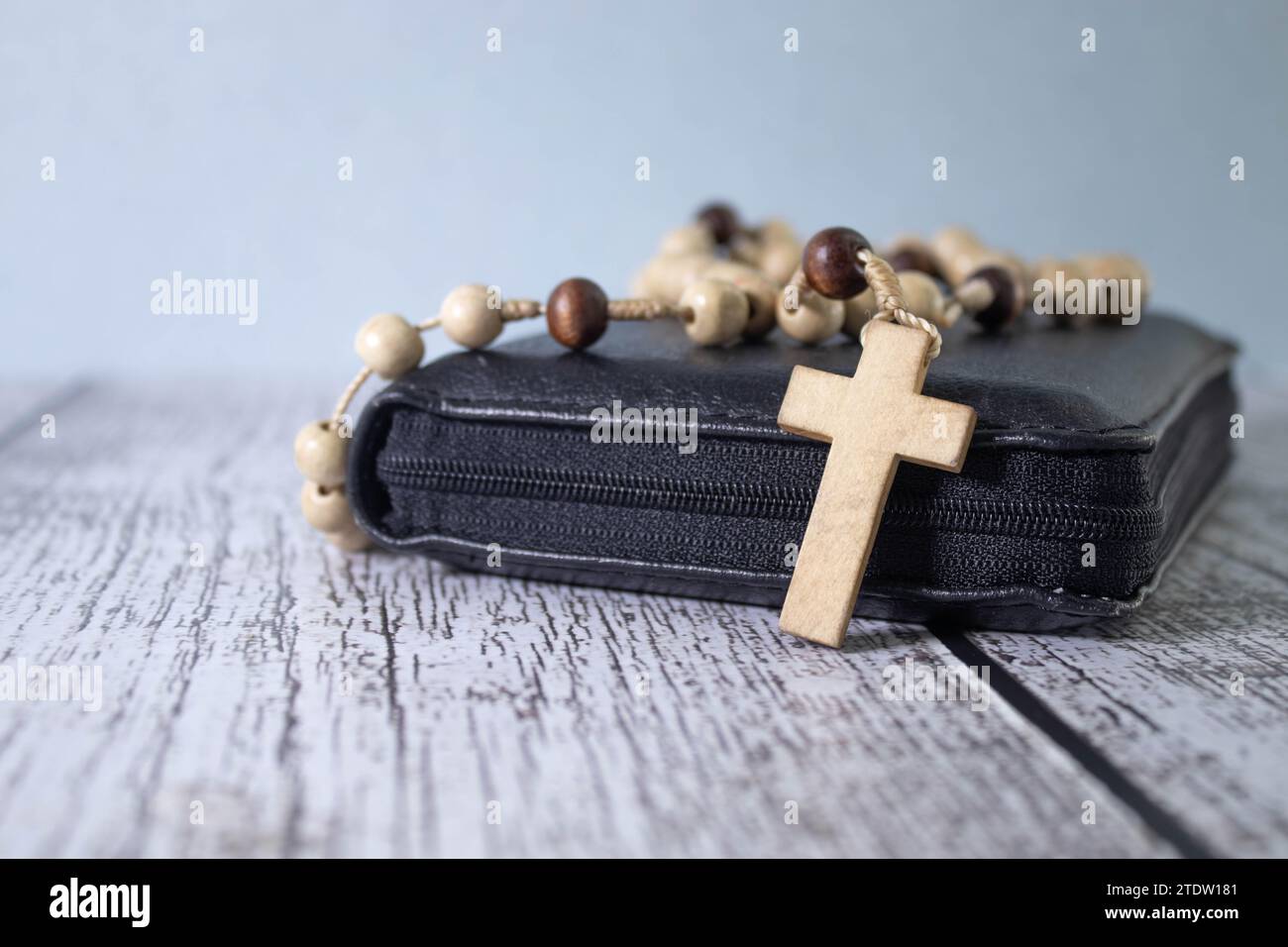 Rosary with cross laying on old Holy Bible book on rustic wooden table ...