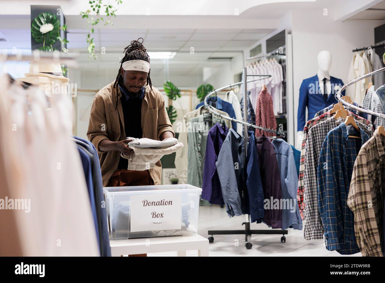 African american man putting clothing in donation box in shopping mall ...