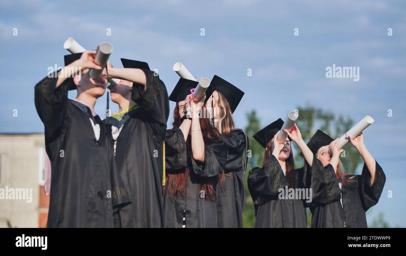 Cheerful graduates on a sunny day look through diplomas like a ...