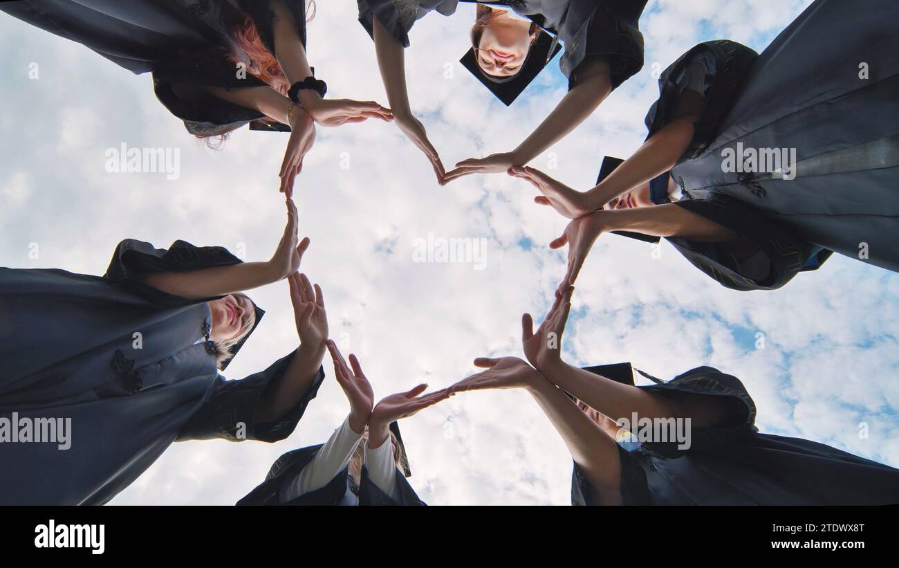 Students graduating from the college make a heart out of their hands ...