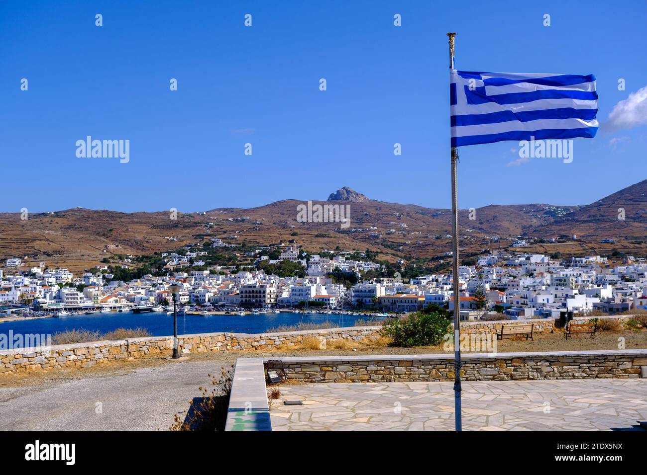 Tinos, GR - 6 August 2023: Greek flag waving over blue sky with Tinos ...