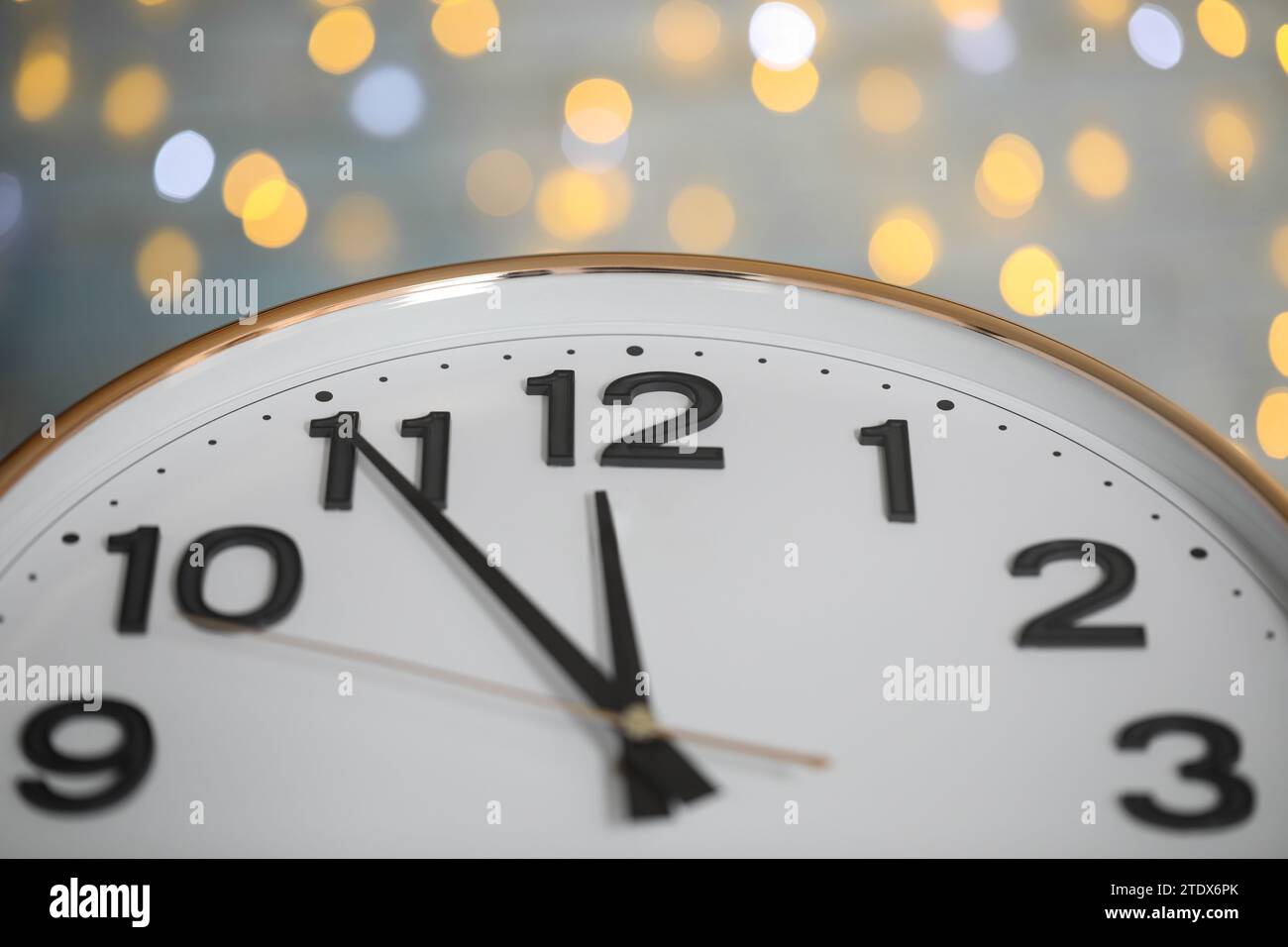 Clock showing five minutes until midnight on blurred background ...