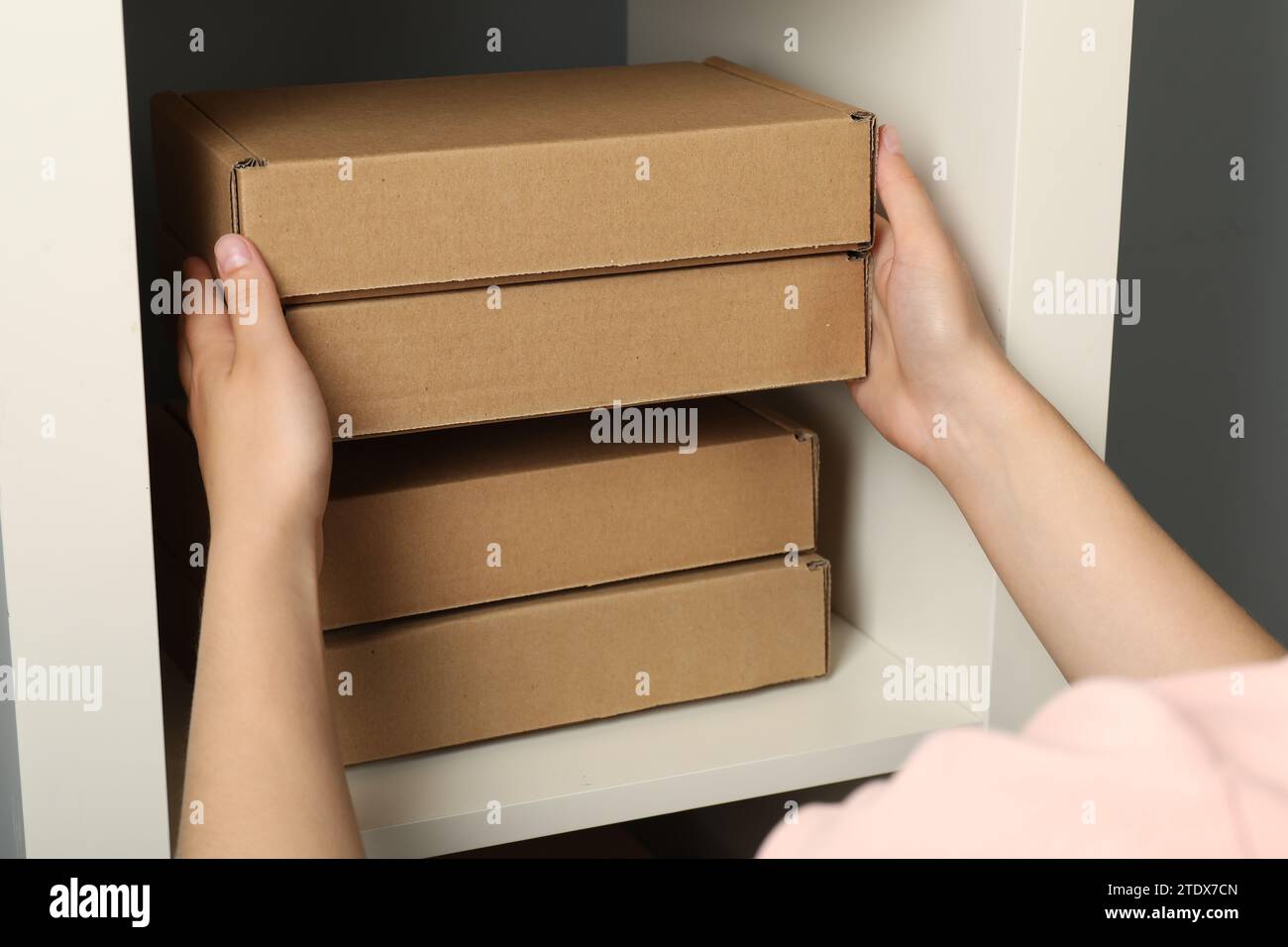 Woman putting cardboard box on shelf, closeup. Packaging goods Stock ...