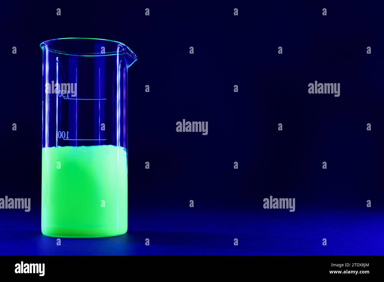 Laboratory beaker with luminous liquid on dark blue background, space ...