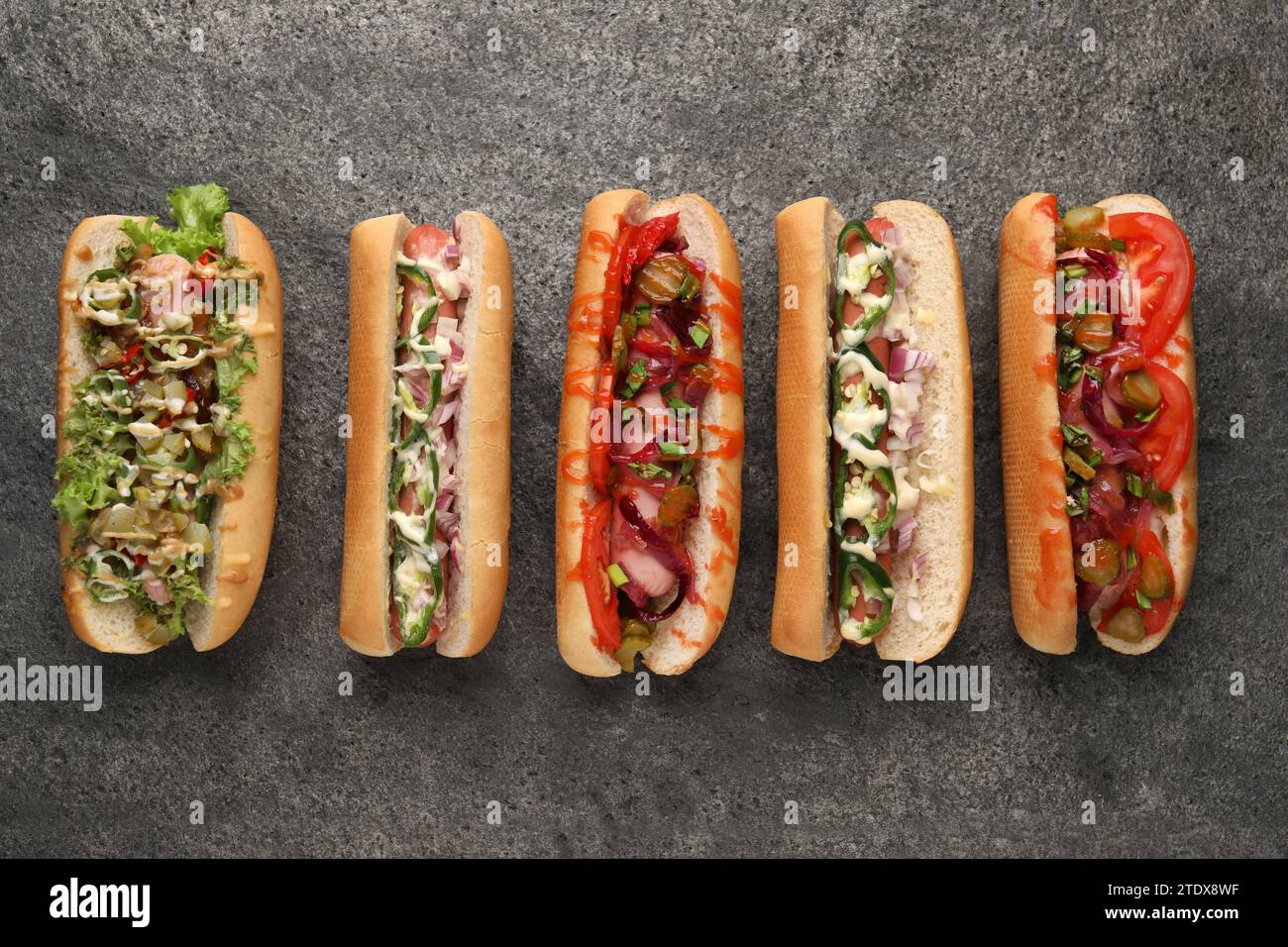Delicious hot dogs with different toppings on grey table, flat lay ...