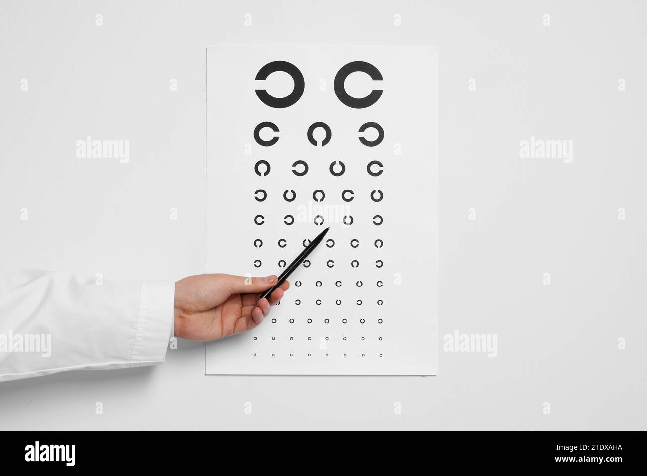 Ophthalmologist pointing at vision test chart on white background ...