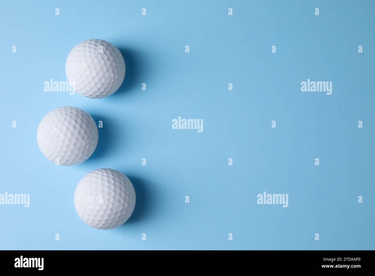 Three golf balls on light blue background, flat lay. Space for text ...