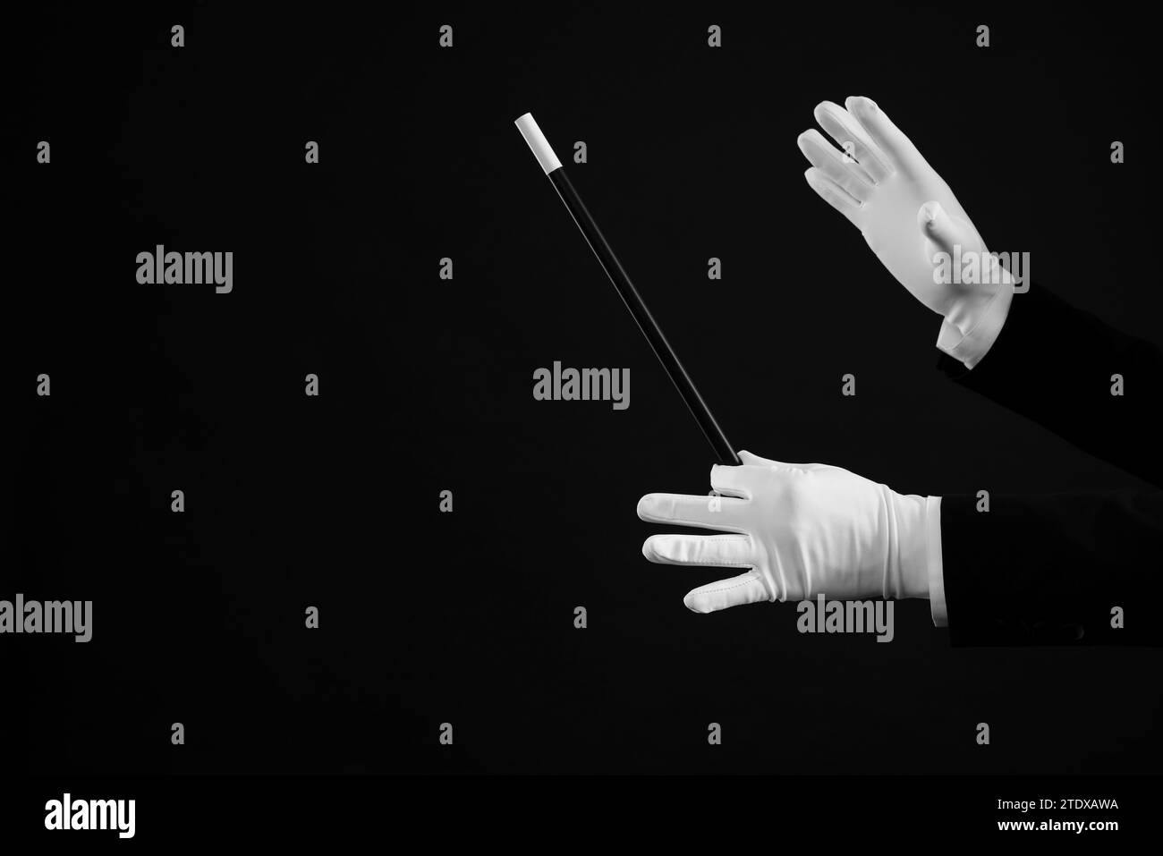 Magician holding wand on black background, closeup. Space for text ...