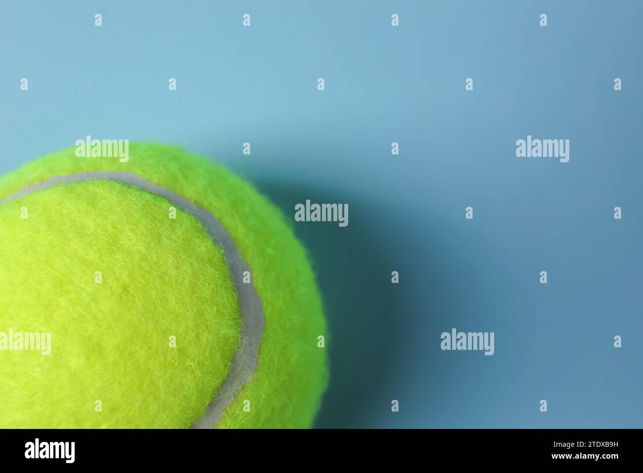 One tennis ball on light blue background, top view. Space for text ...