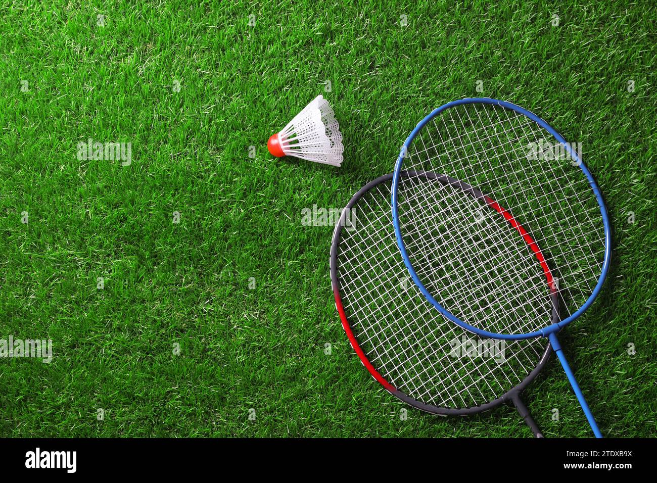Two badminton rackets and shuttlecock on green grass, top view with ...