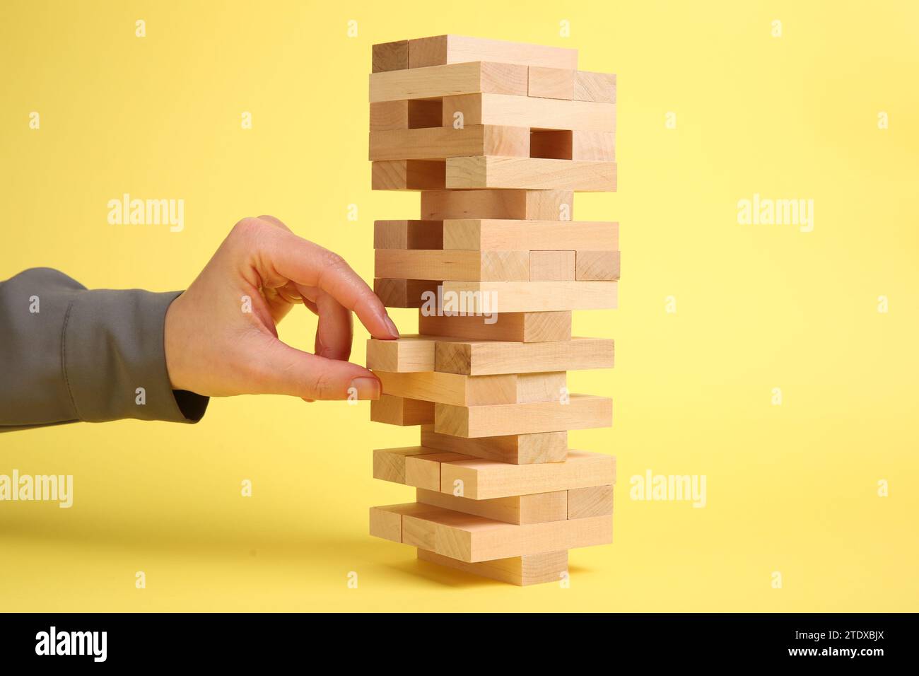 Woman playing Jenga tower on yellow background, closeup Stock Photo - Alamy