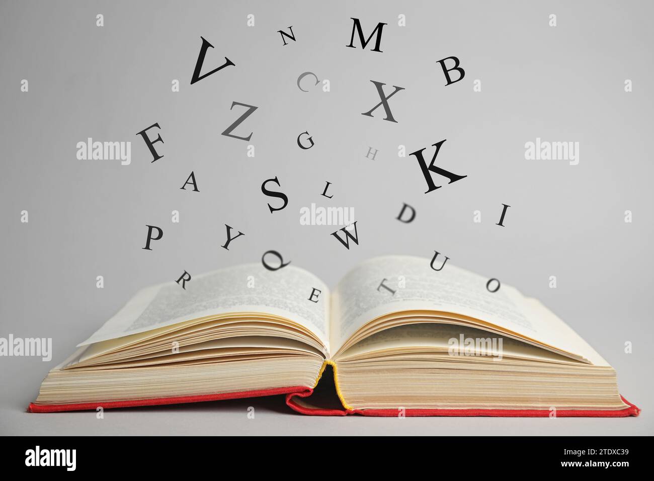 Open book with letters flying out of it on light background Stock Photo - Alamy
