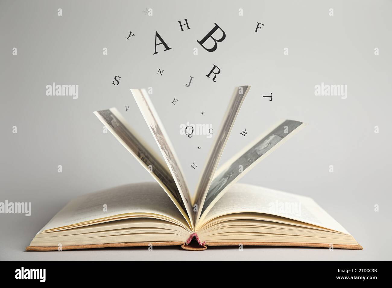 Open book with letters flying out of it on light background Stock Photo ...