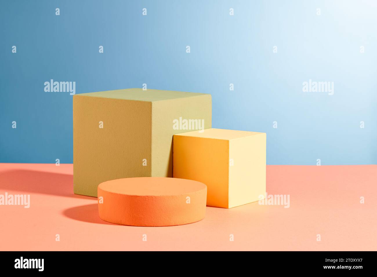 Three podiums in round and cube shaped are decorated against blue ...