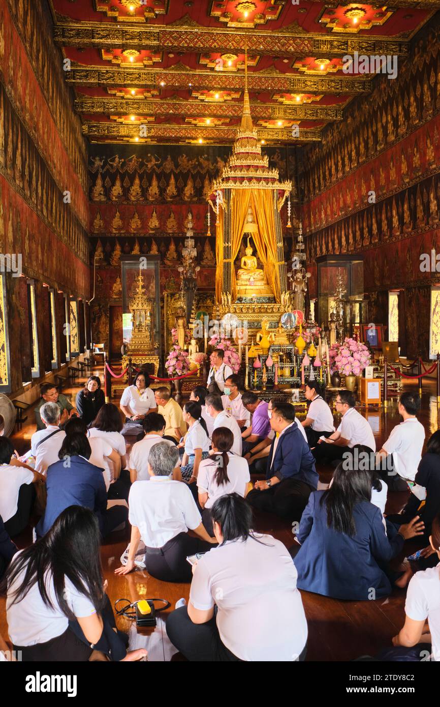 A group of worshippers, busy praying. Inside the red, richly decorated ...