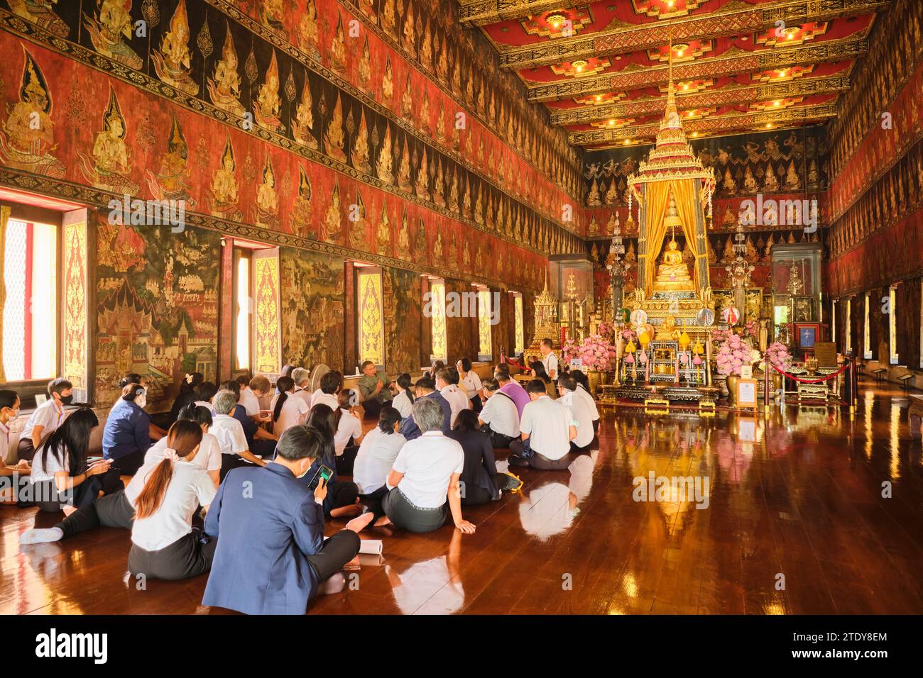 A group of worshippers, busy praying. Inside the red, richly decorated ...