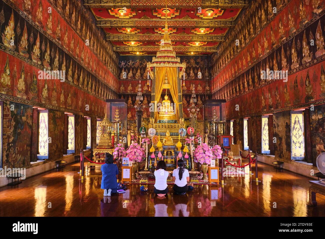 A few kneeling worshippers, busy praying. Inside the red, richly ...