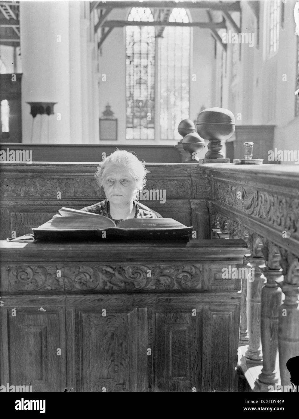 Sexton woman with bible in church pew in the Grote Kerk in Edam ca ...