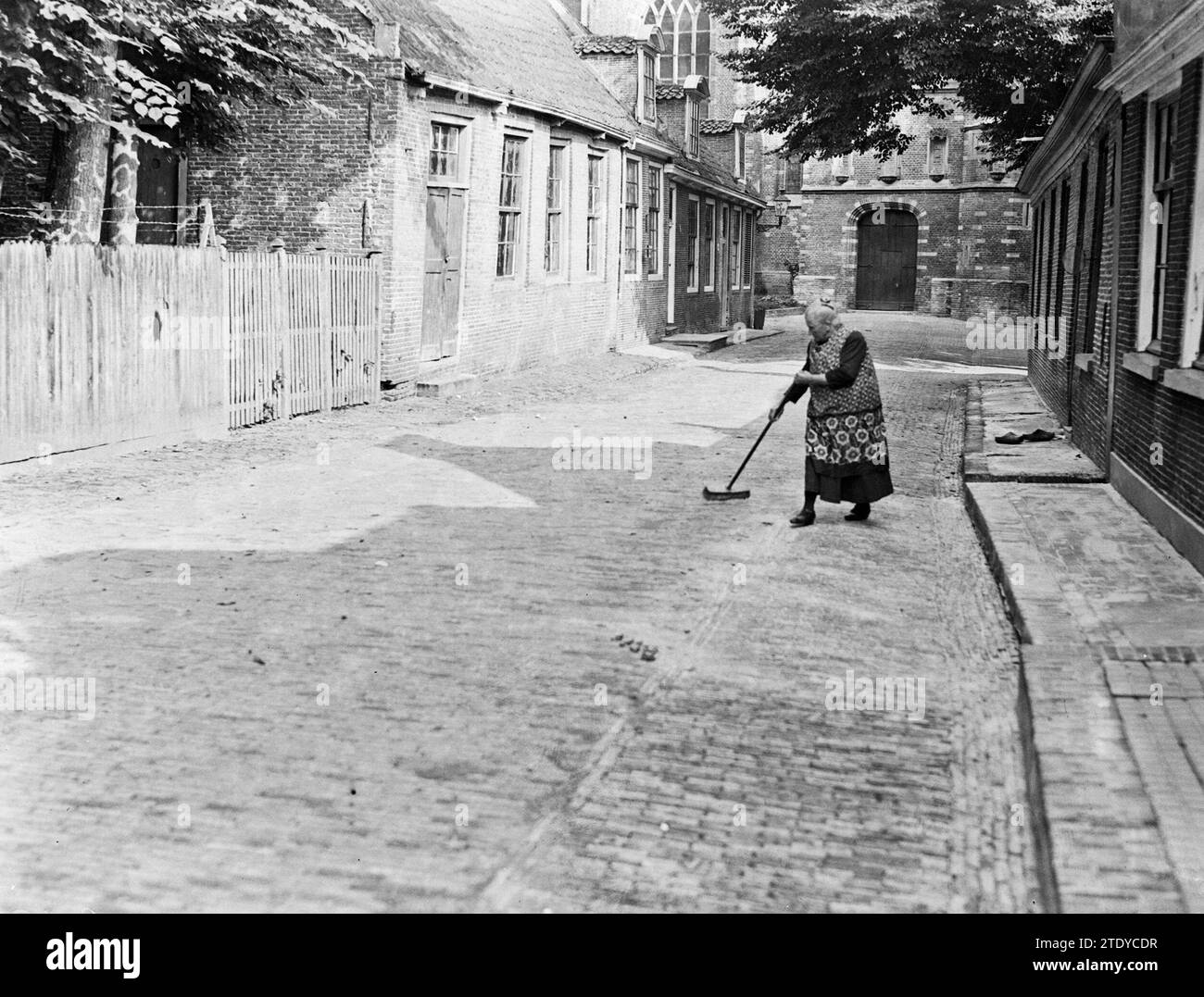 Street in Edam with sweeping woman, in the background a church ca. 1932 ...