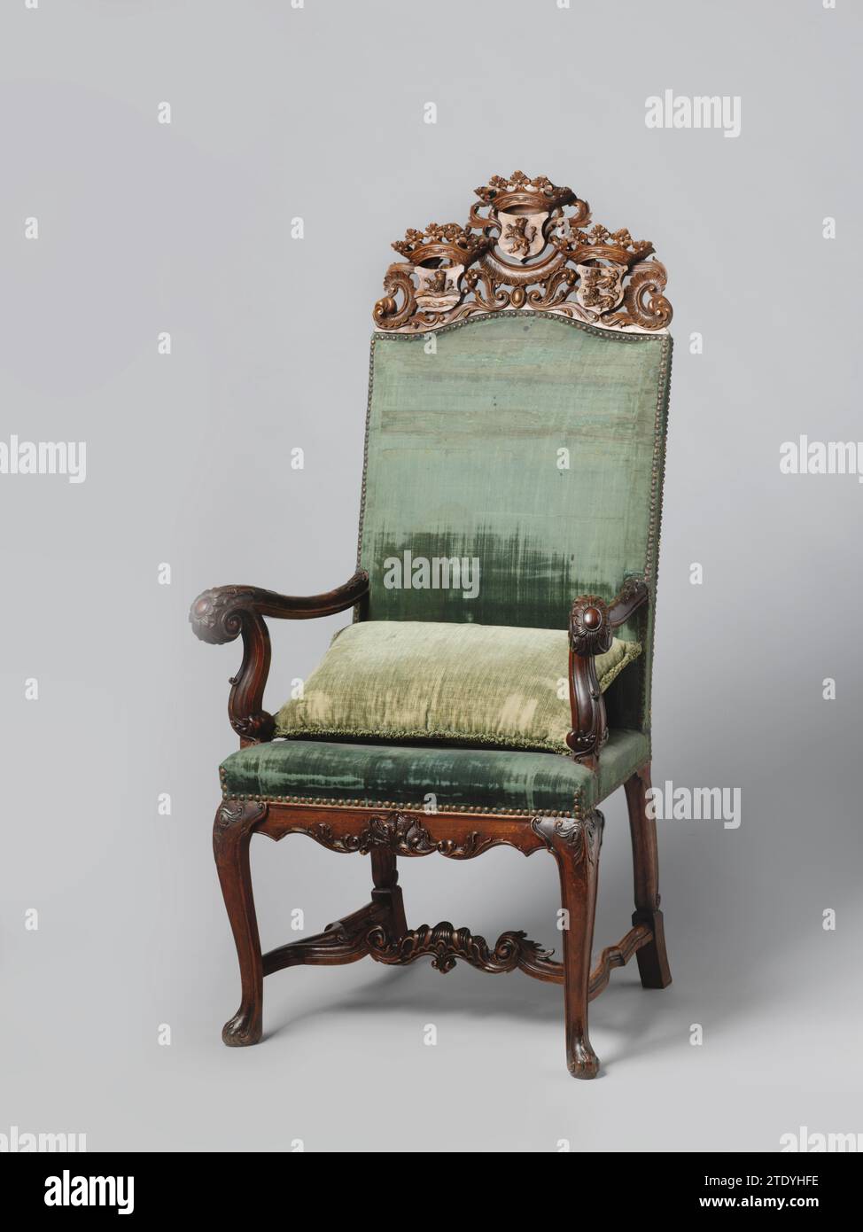 Arm chair of walnut, covered with green velvet. On the back an ...