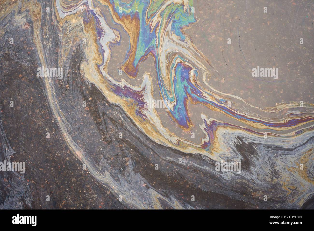 Rainbow-colored oil floating on water after rain on asphalt. Gasoline ...