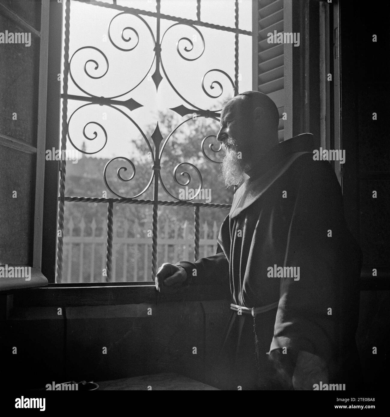 Monk in front of window with cast iron fence of the Church of the agony ...