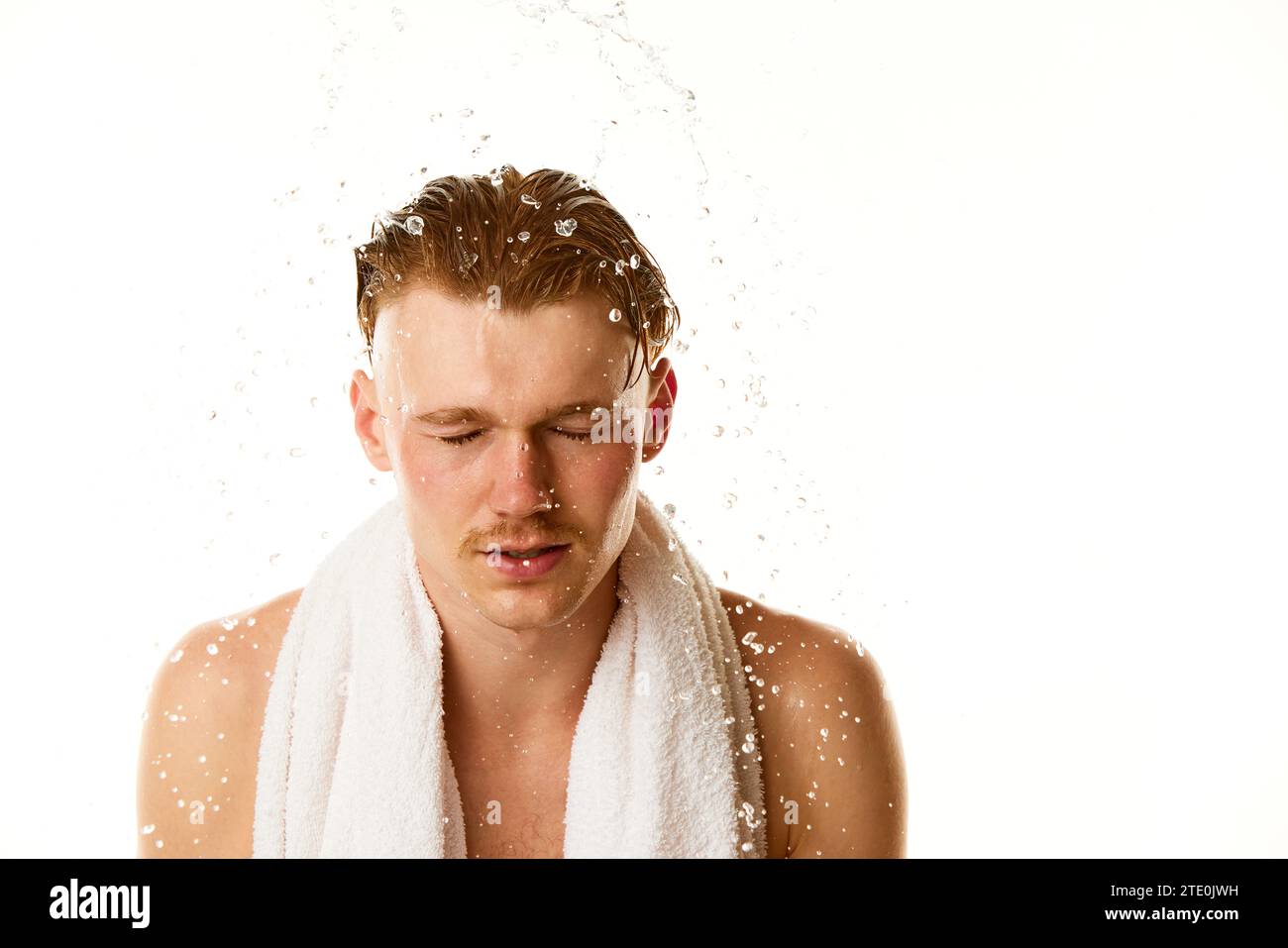 Morning routine. Pleased, handsome redhaired male model washing face in ...