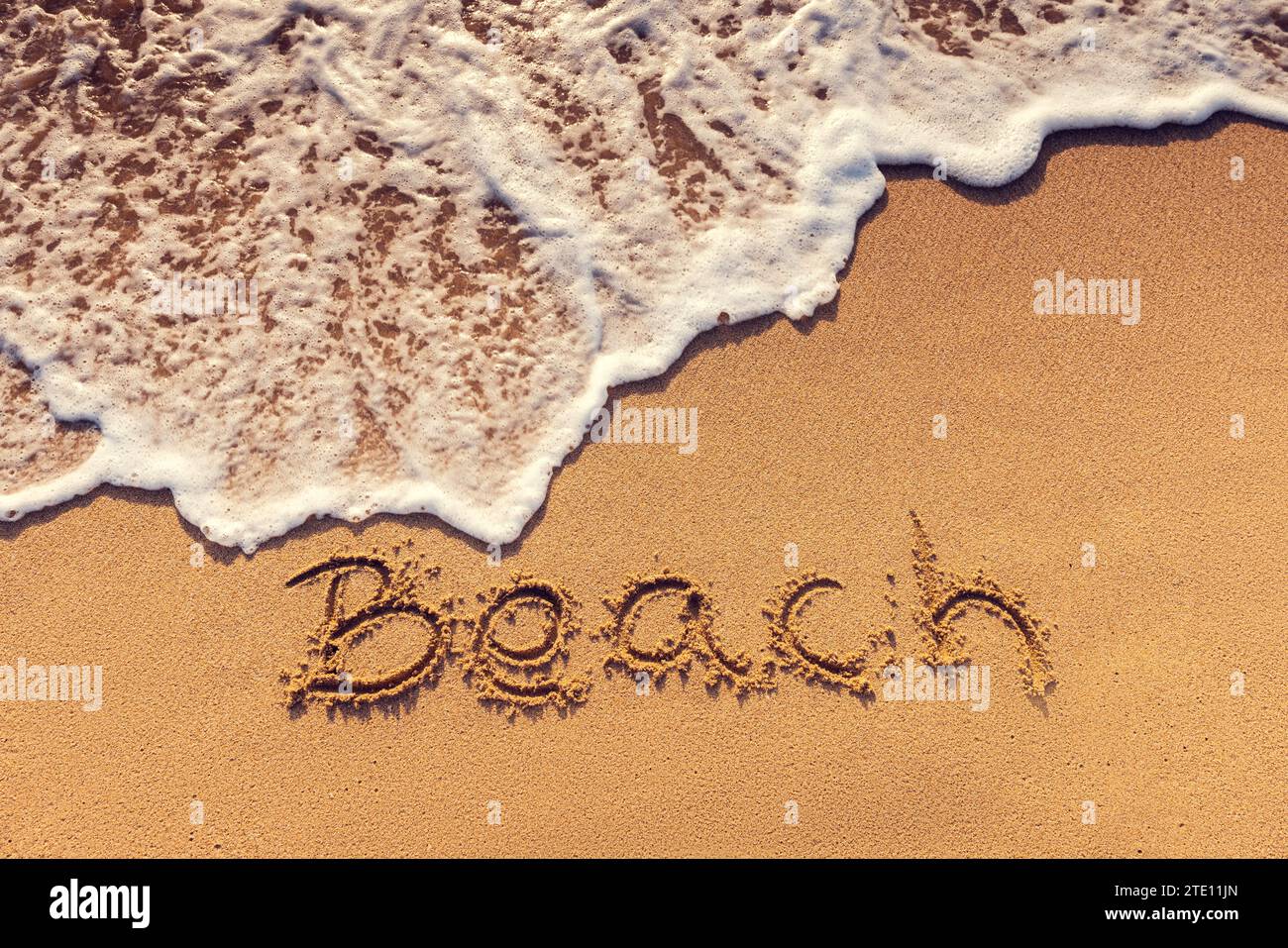 Beach handwritten text on the sand of tropical island shore and ocean ...