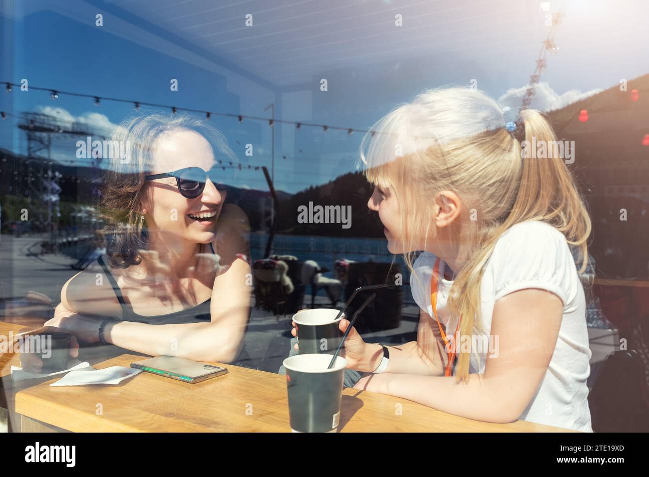 Through window view of young adult happy mom enjoy having fun talking ...