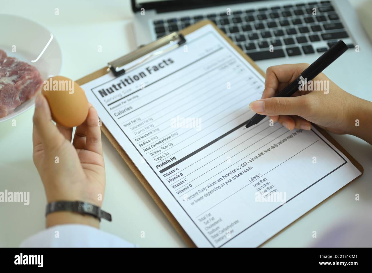 Closeup nutritionist holding an egg and writing diet plan, creating ...
