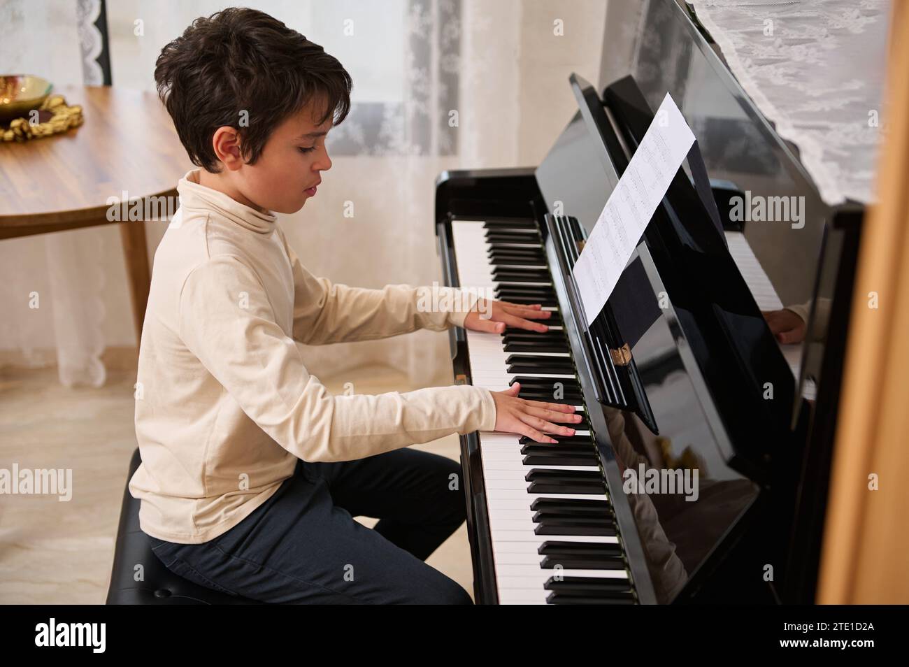 Adorable dark haired preteen child boy plays grand piano during music ...