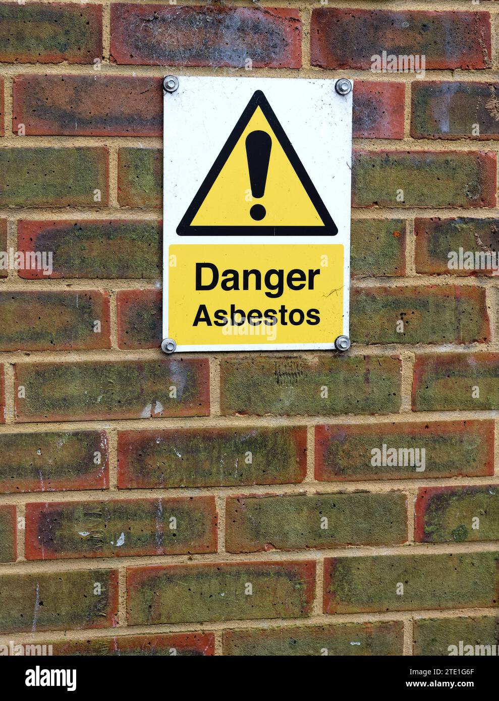 A danger warning sign on a brick wall indicating the presence of ...
