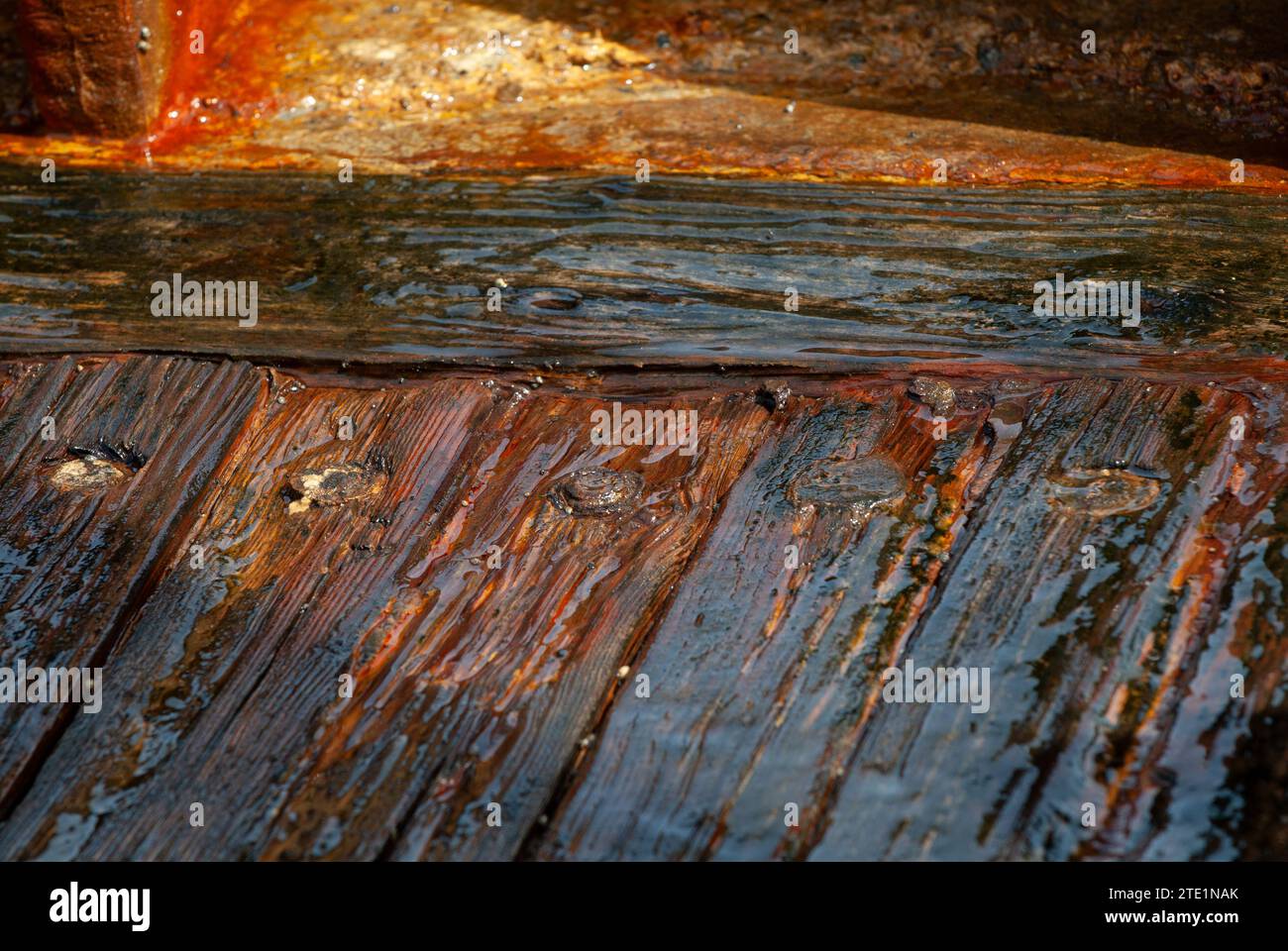 Wet, shiny, cracked and worn floor boards of an old, wooden ship wreck ...